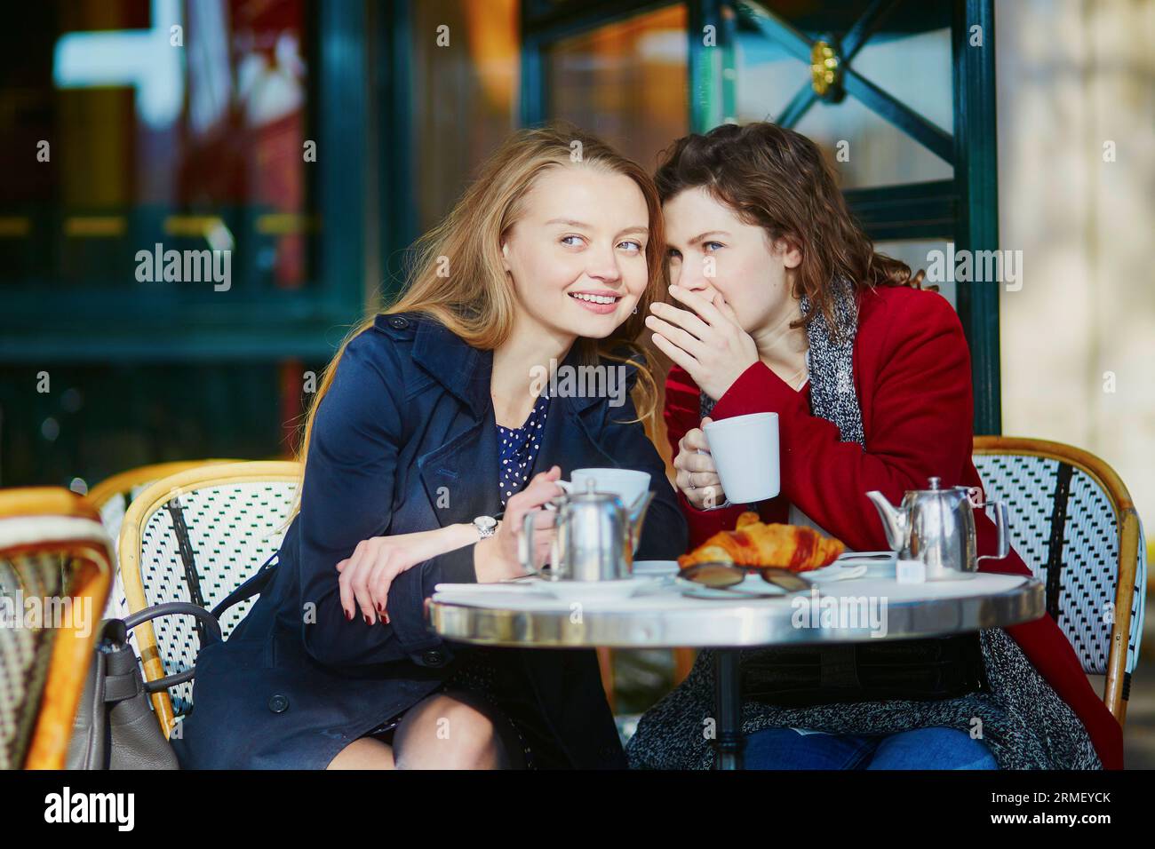 Deux jeunes filles dans un café en plein air parisien, boire un café ...