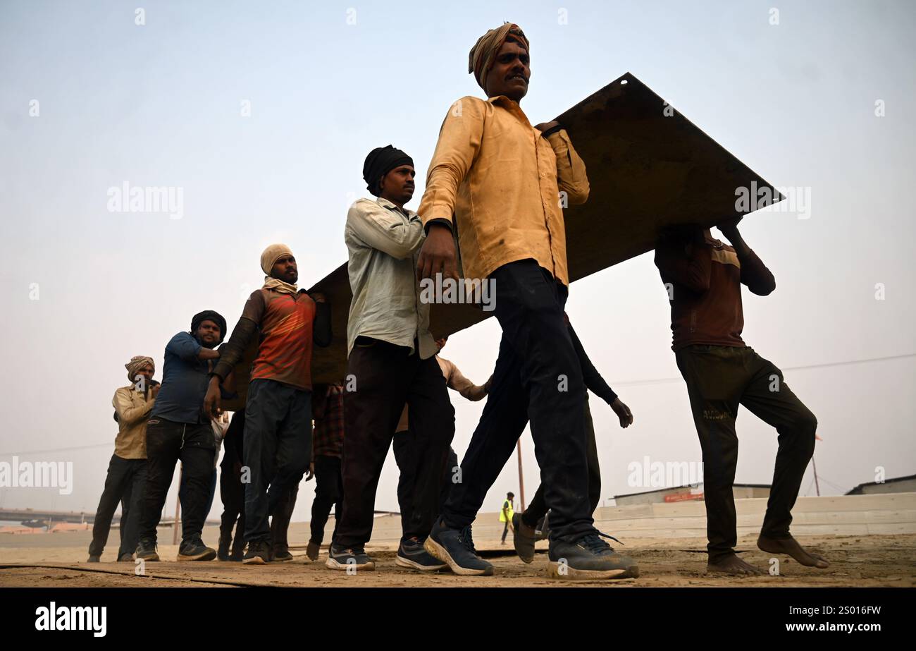 Prayagraj, Inde. 23 décembre 2024. Les ouvriers transportent des ...