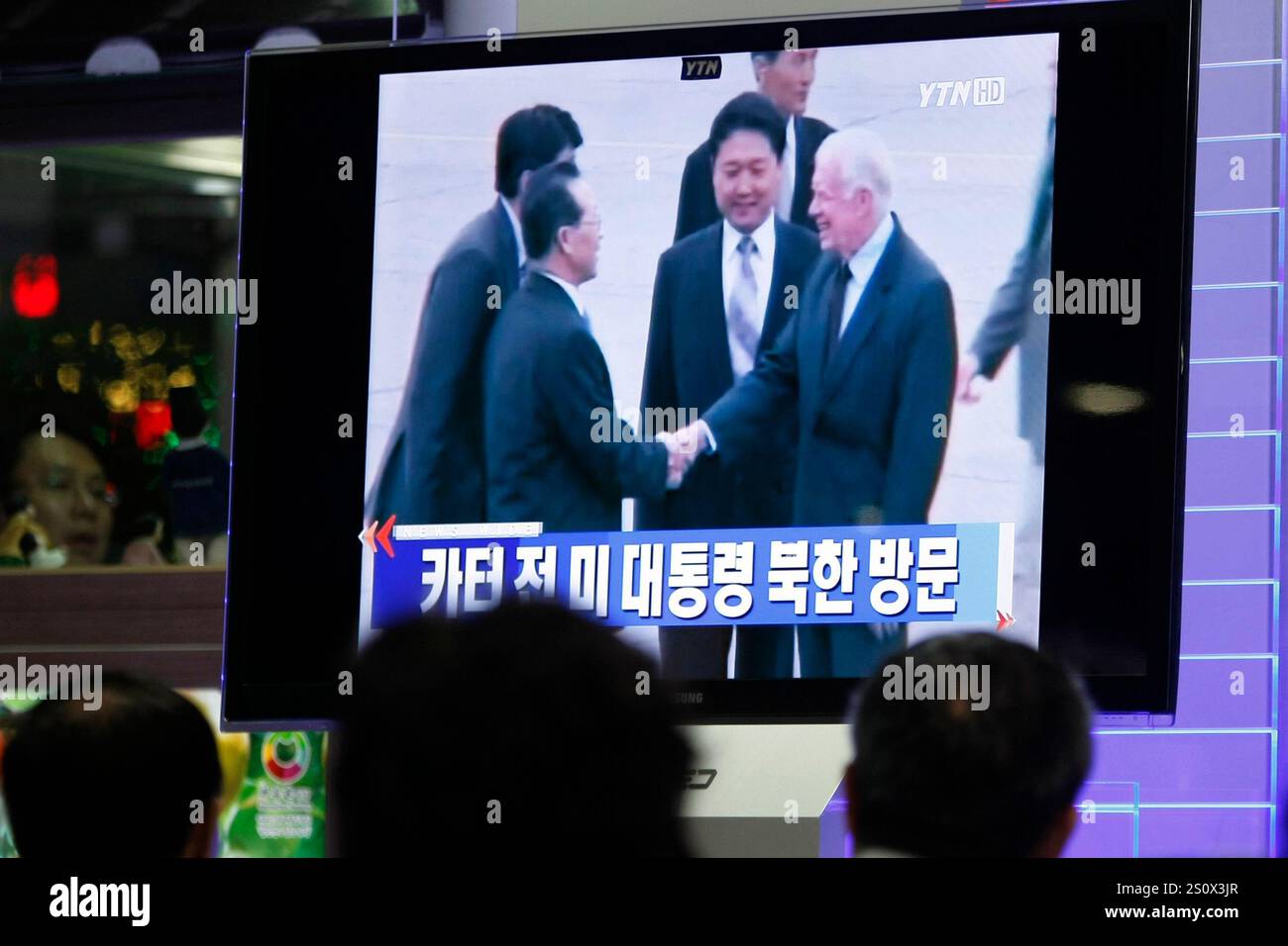FILE - South Koreans watch a TV news program showing former President ...
