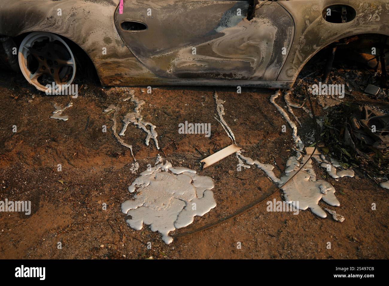 Melted metal from a burned vehicle is seen on the ground of a property ...