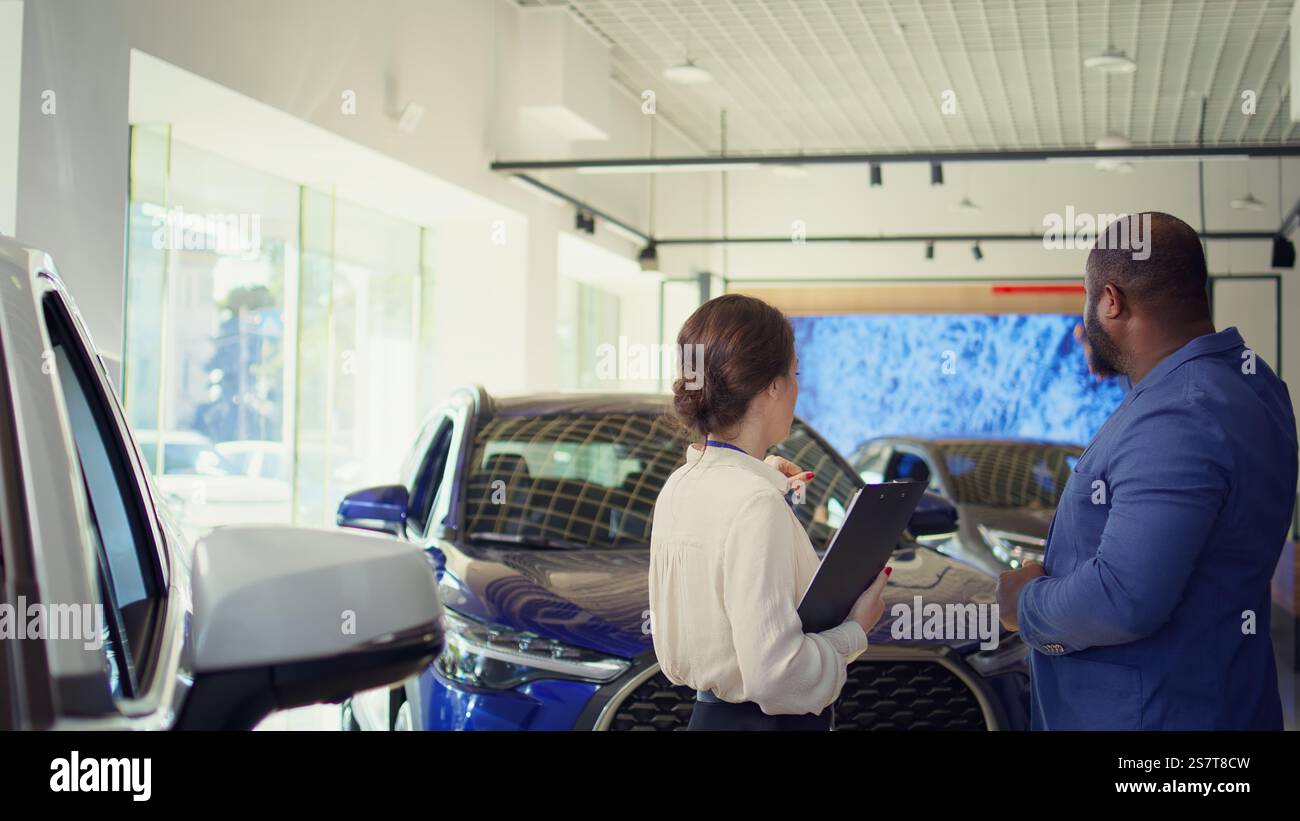 Vendeuse de la concession discutant avec le client, observant et notant ses préférences, ses ...
