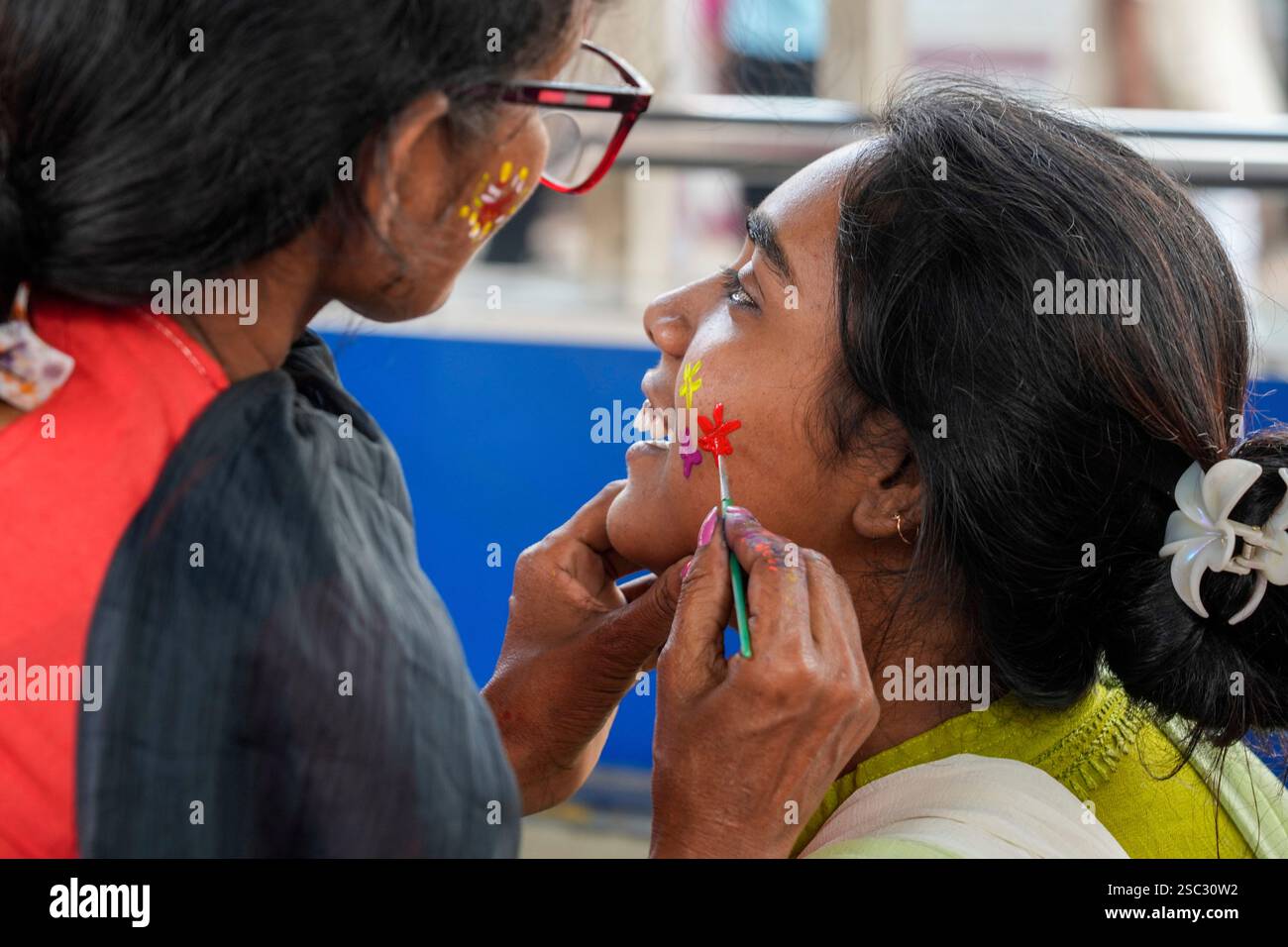 An activist paints another's face prior to joining a rally during a ...