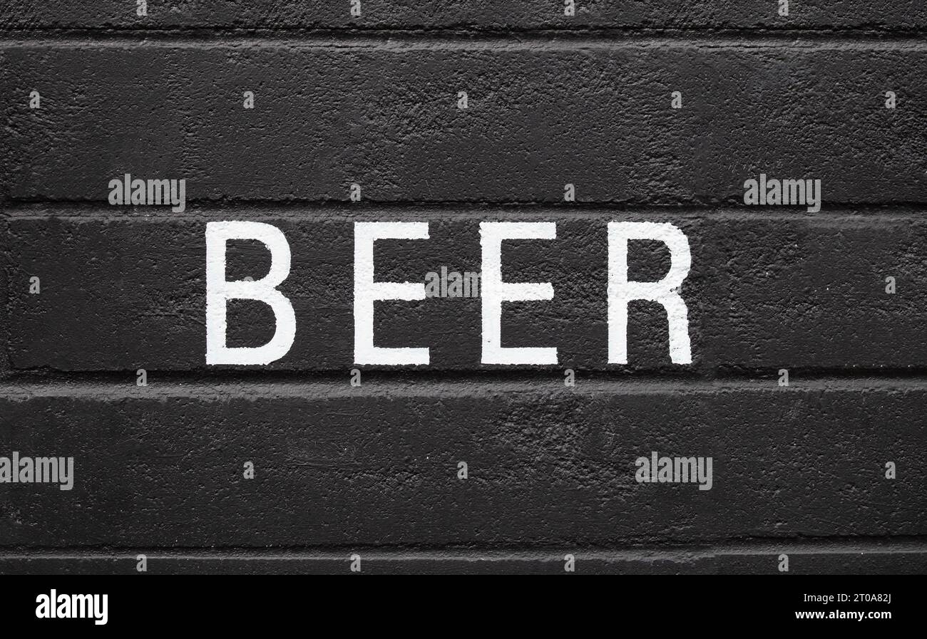 Bière peinte sur mur de béton noir. Lettres majuscules blanches sur ...