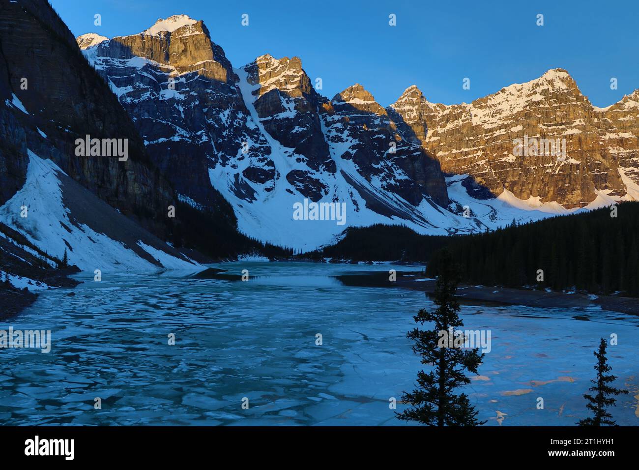 Première lumière de l'aube au lac Moraine avec un lever de soleil doré au-dessus de la vallée ...