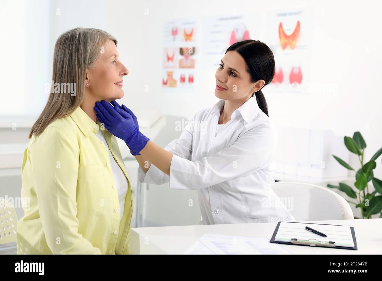 Endocrinologue examinant la glande thyroïde d'un patient à table à l ...