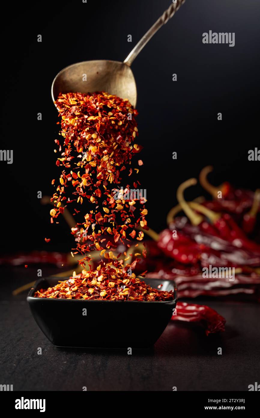 Les flocons de piment sont versés dans un plat noir. Flocons de piment ...