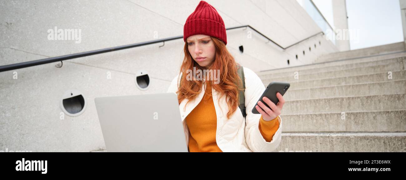 Portrait de femme à tête rouge assis sur un escalier, utilise un ...