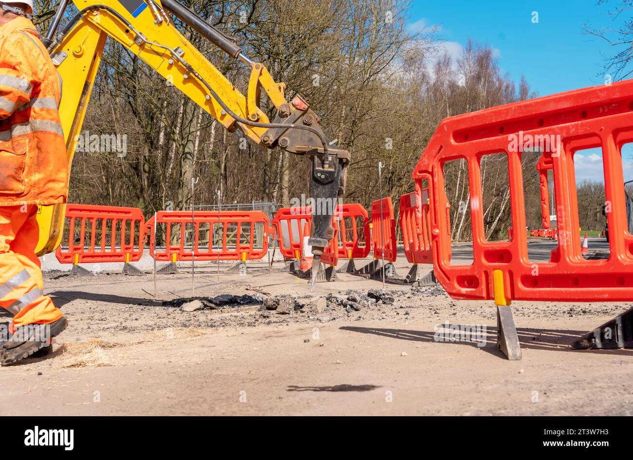 Excavatrice cassant et forant le béton et la surface de la route. Grand ...
