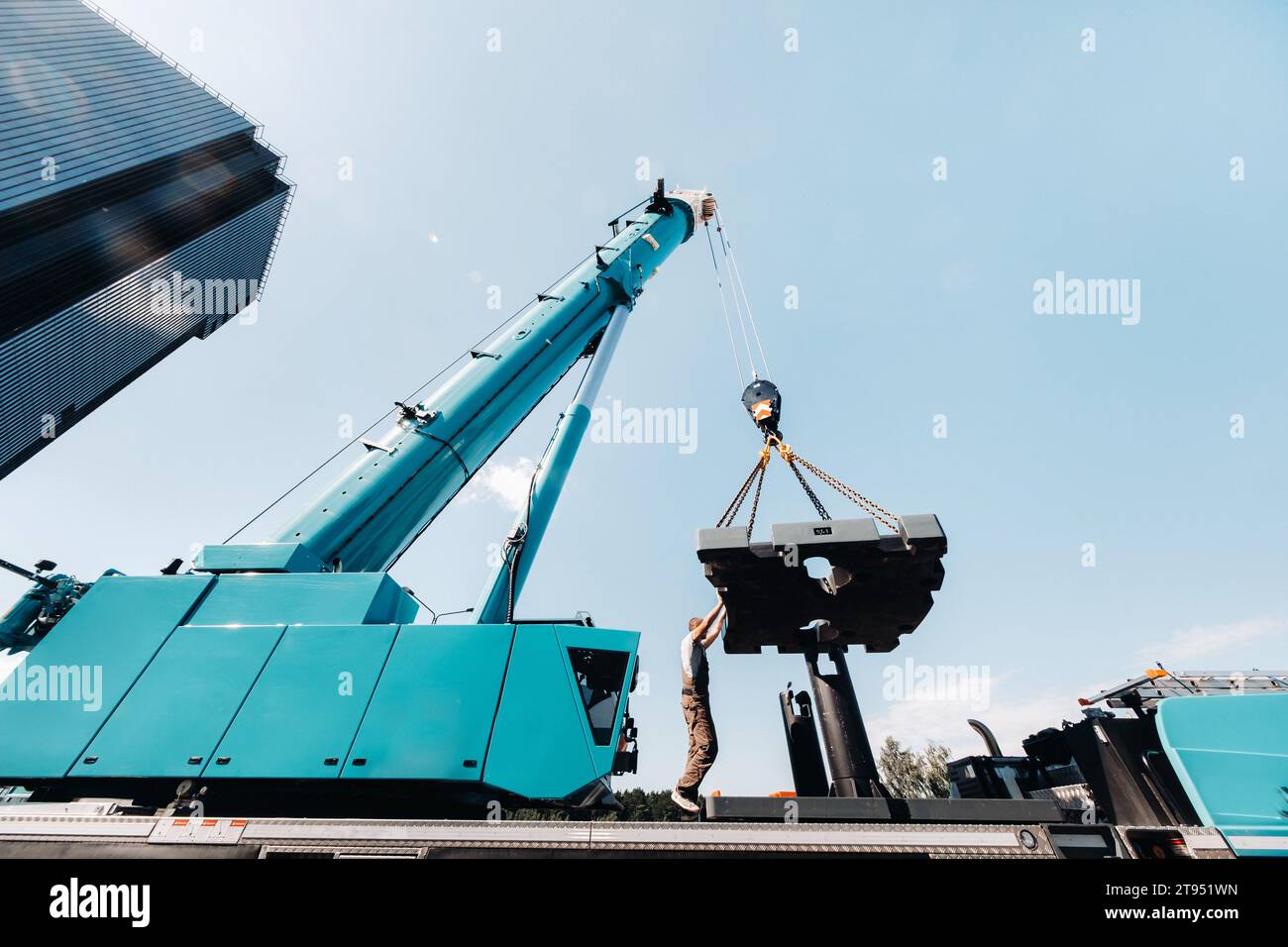 le contrepoids est installé par un ouvrier méconnaissable sur une grande grue de voiture bleue ...