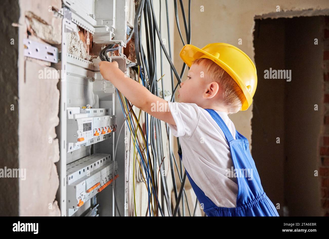Petit garçon électricien tenant les fils électriques tout en fixant le ...