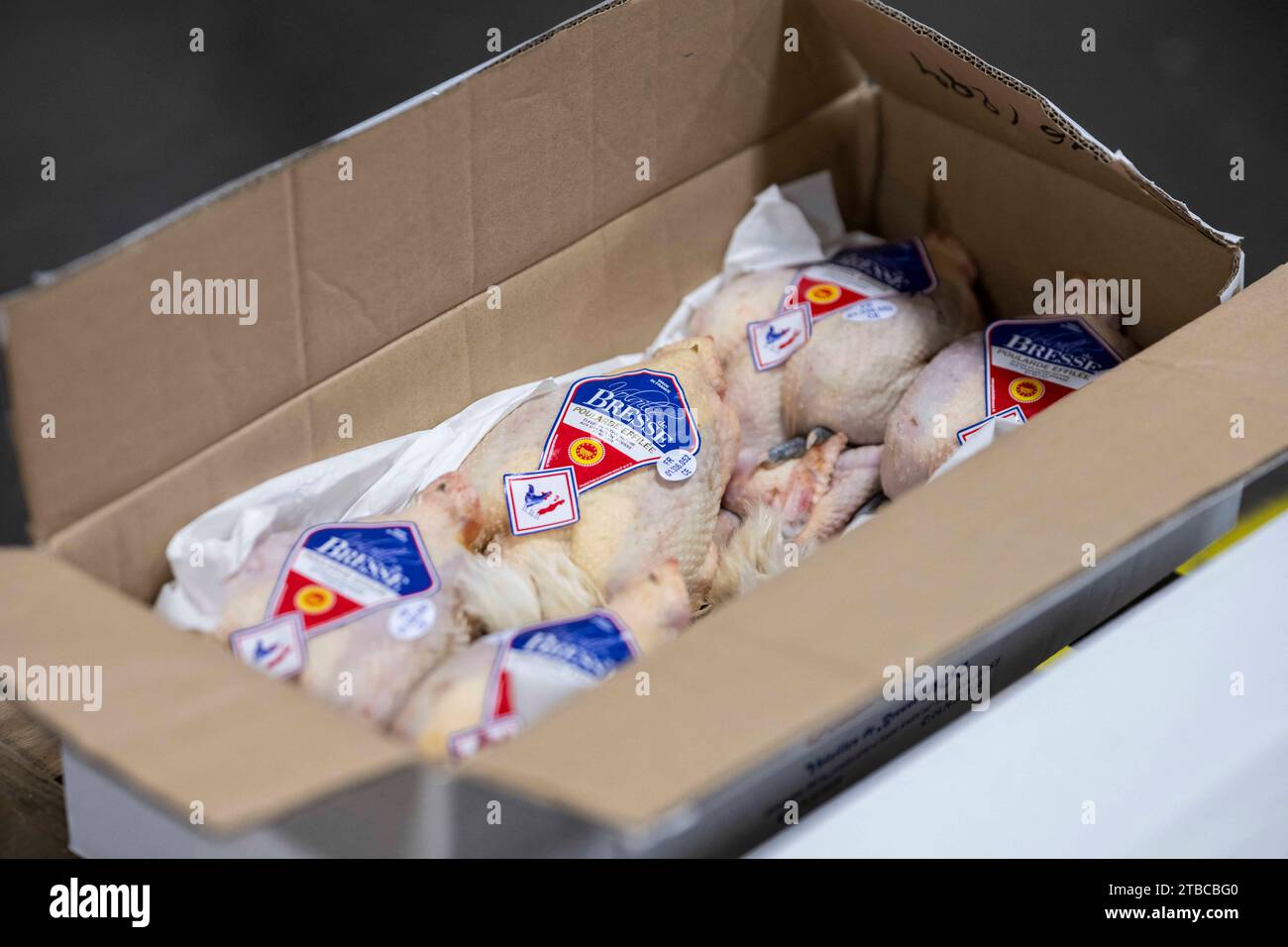 Cette photographie montre un employé qui travaille avec de la volaille ...