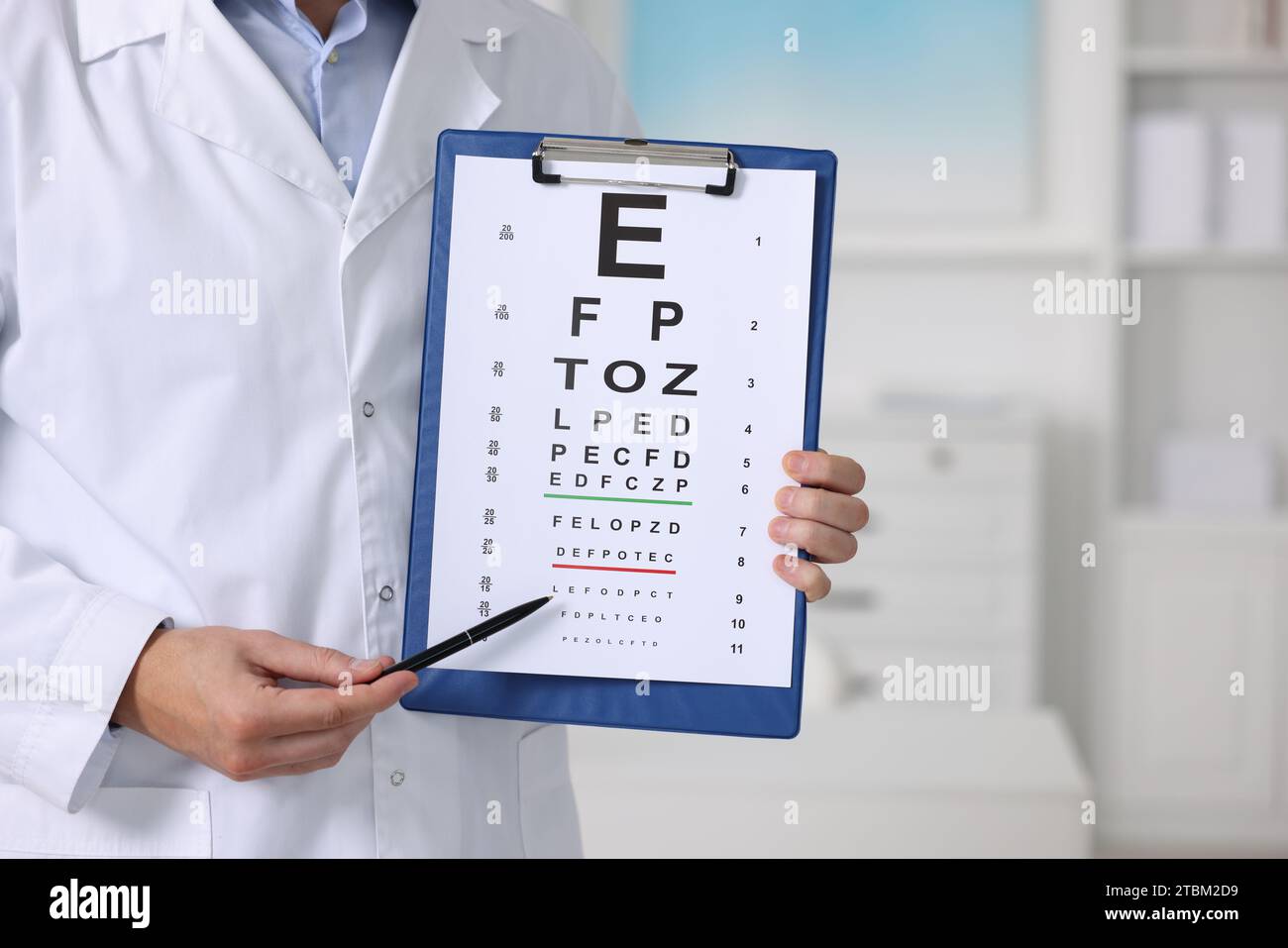 Ophtalmologiste pointant le tableau de test de vision en clinique, gros ...