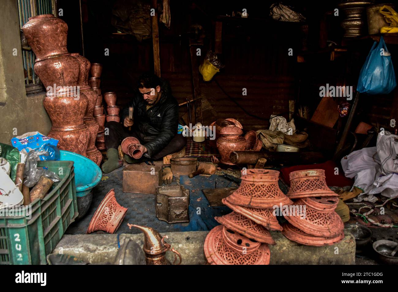 Un Kashmiri Coppersmith travaille sur un ustensile en cuivre dans un ...