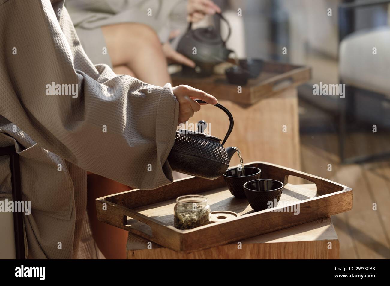 Théière en fonte noire avec tisane installée sur plateau en bois ...