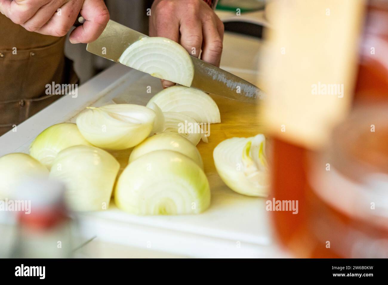 Gros plan des mains d'un chef anonyme qui tranchent des oignons, en ...