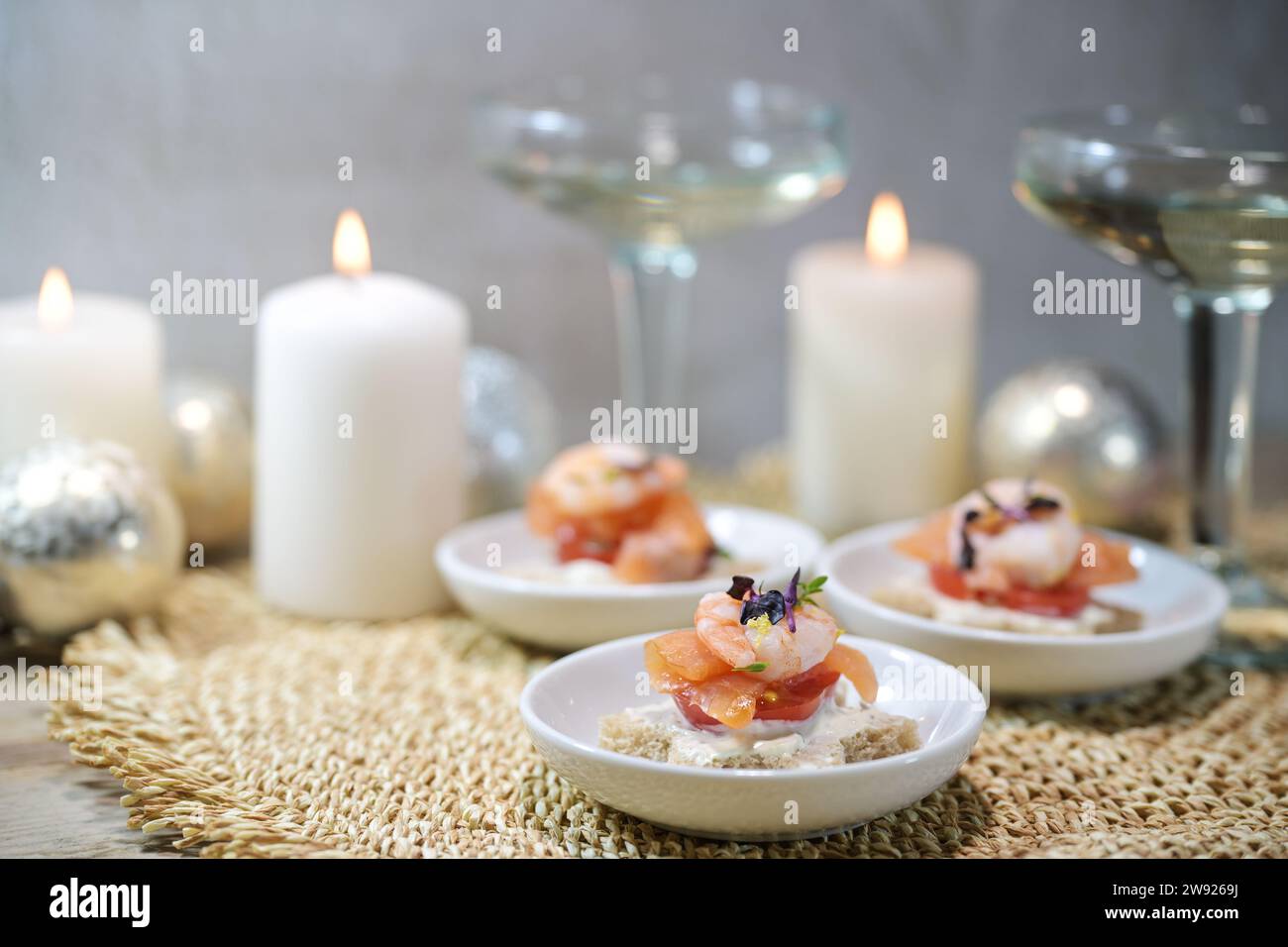 Canapés festifs avec crevettes et saumon, verres à champagne et bougies ...