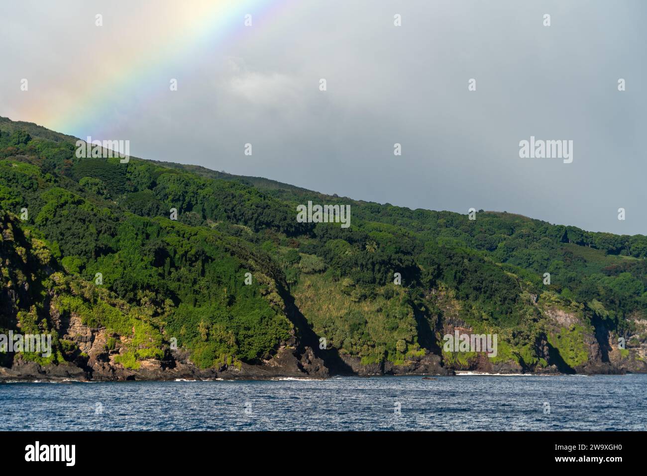 Un arc-en-ciel brillant s'étend dans le ciel au-dessus des falaises ...