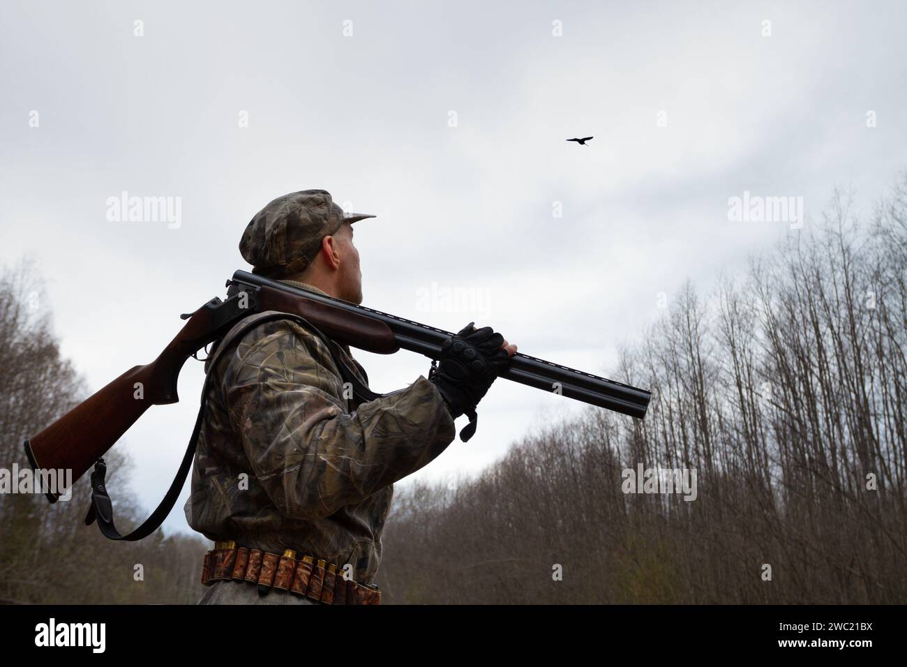 Un chasseur avec un fusil de chasse déchargé sur son épaule se tient au ...