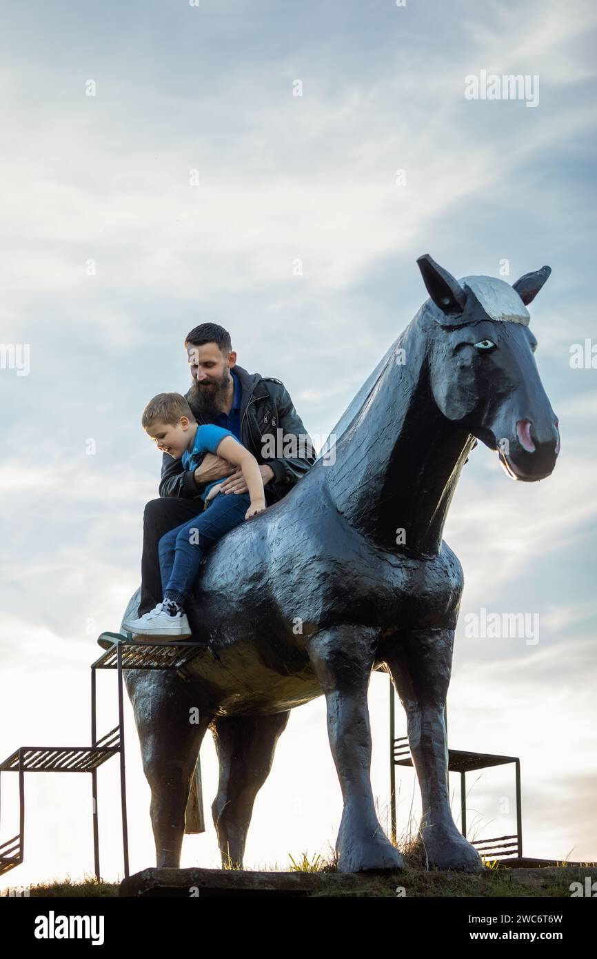 Portrait d'un père et de son petit fils sur un gros cheval noir sur ...