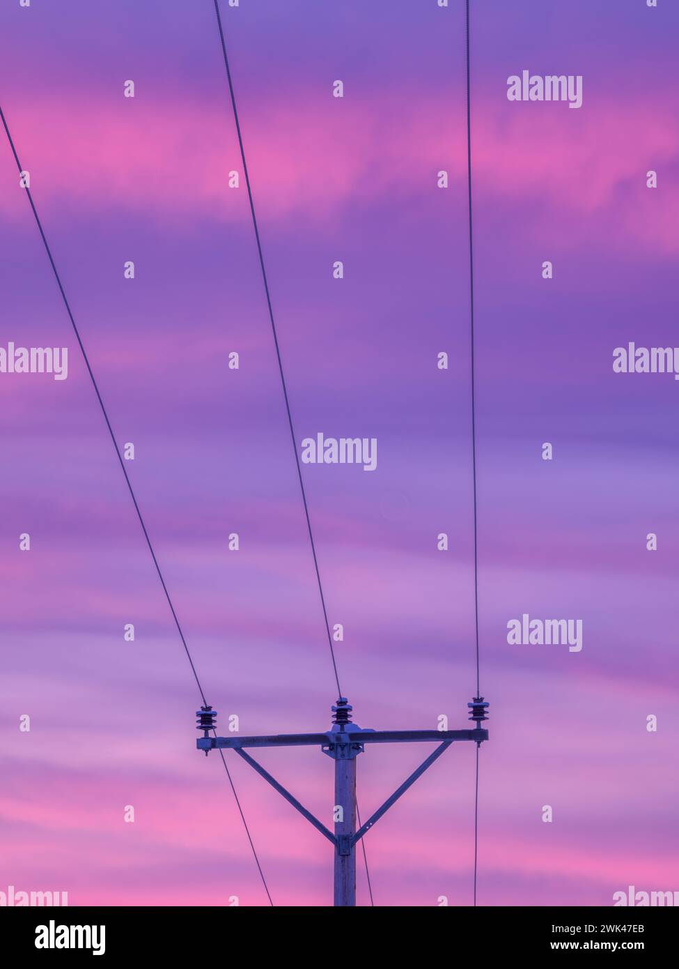 Cette image capture la silhouette d'un pylône électrique posé contre un ciel lever de soleil à ...