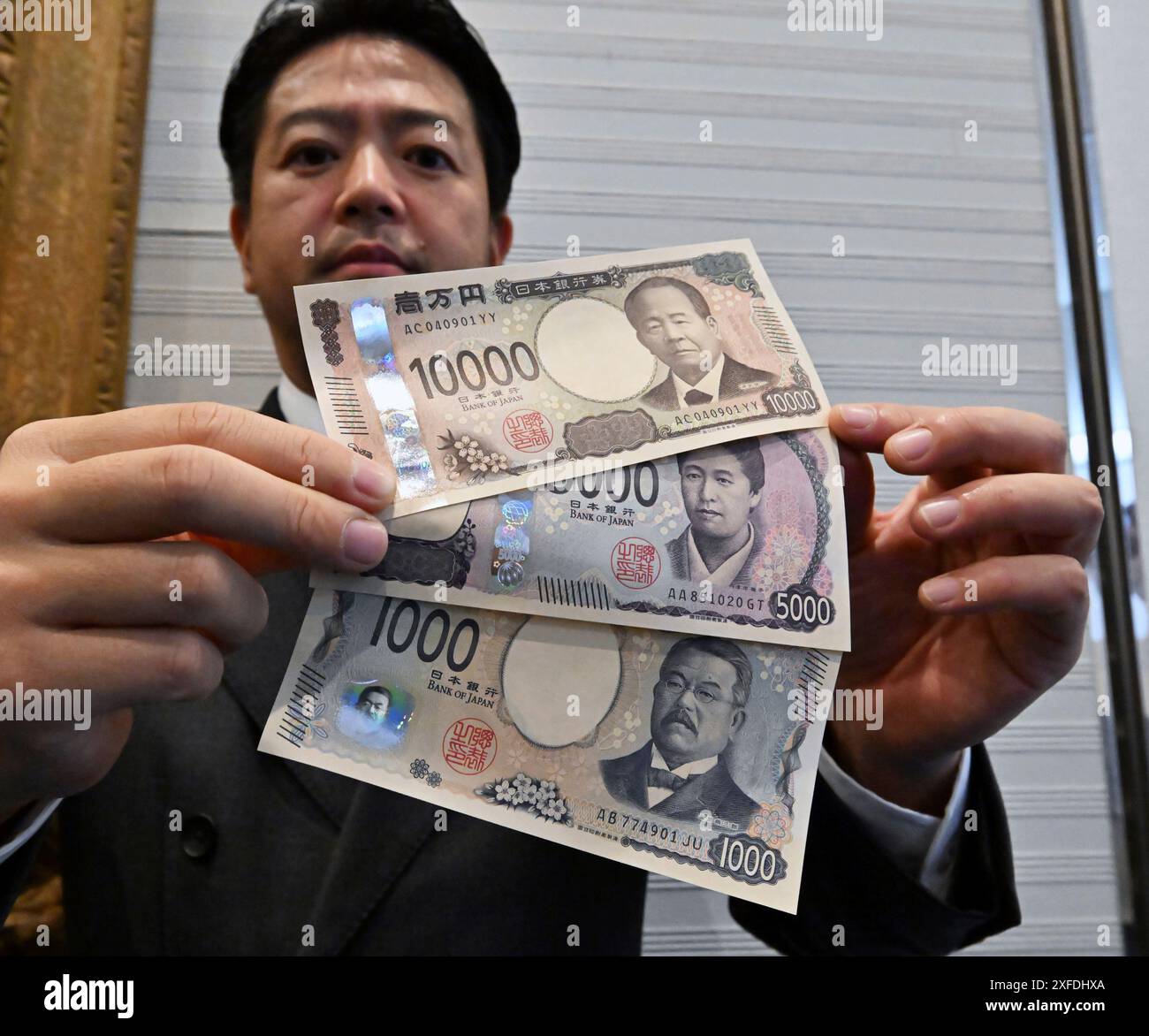 A man shows three types of new banknotes which were issued for the ...