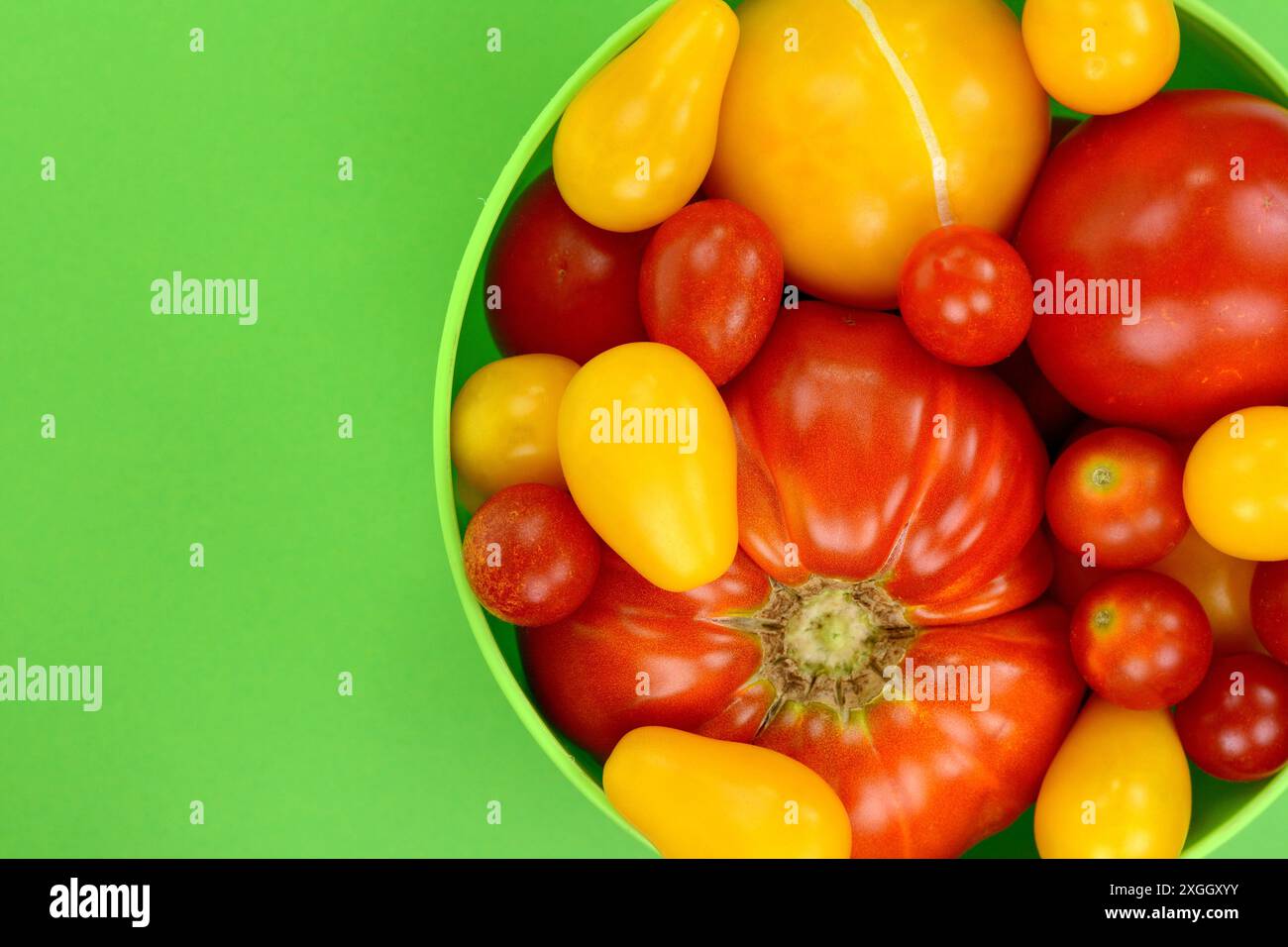 Différents types de tomates biologiques dans un bol isolé sur fond vert ...