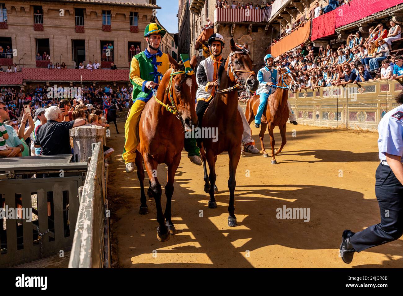 Les jockeys portant leurs couleurs Contrada approchent de la ligne de ...
