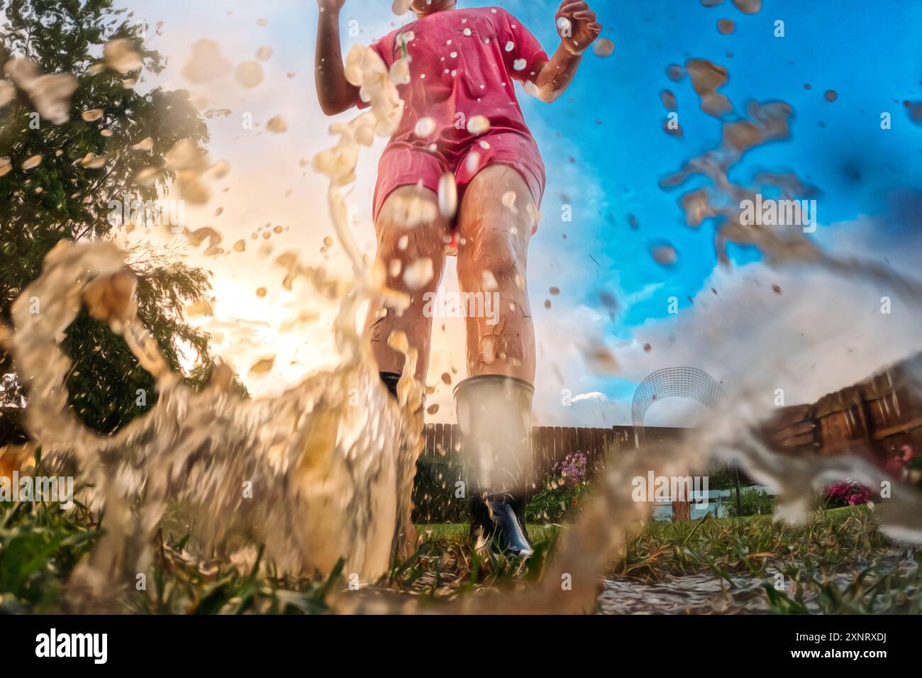 Fille sautant dans une flaque d'eau boueuse Banque de photographies et ...
