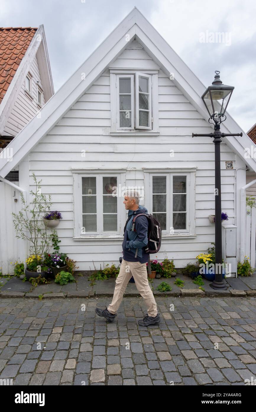 Un touriste passe devant une maison traditionnelle en bois blanc dans ...