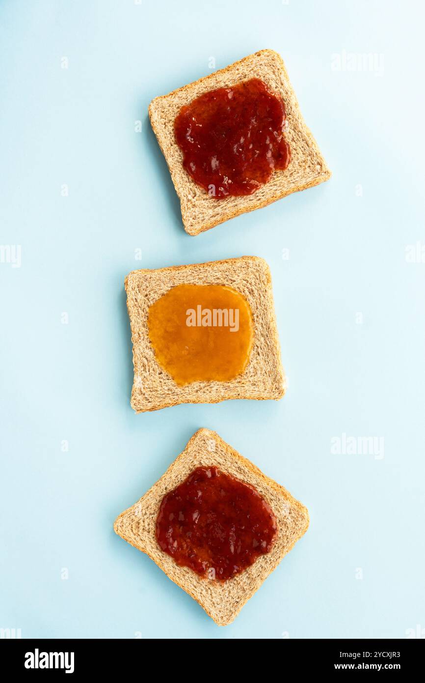 Trois tranches de pain de blé avec différents types de confiture, de fraise et de pêche, servies ...