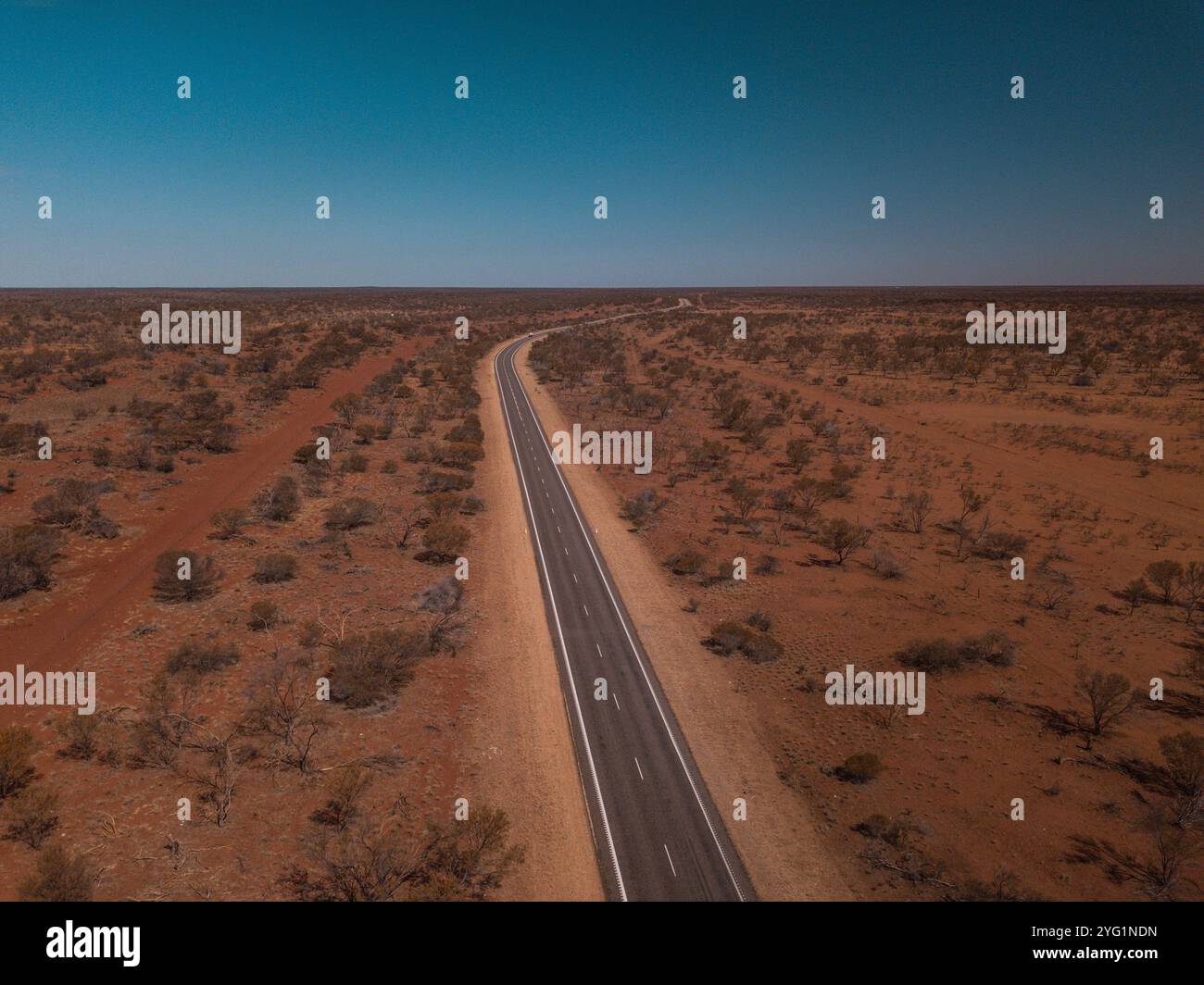 Tronçon de route dans l'Outback se courbant avec la terre, arborant des ...