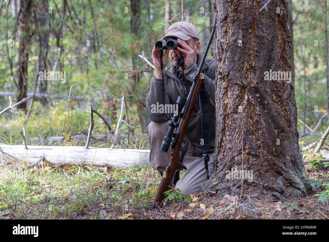 Chasseur se cachant derrière un arbre, regardant les environs avec des ...