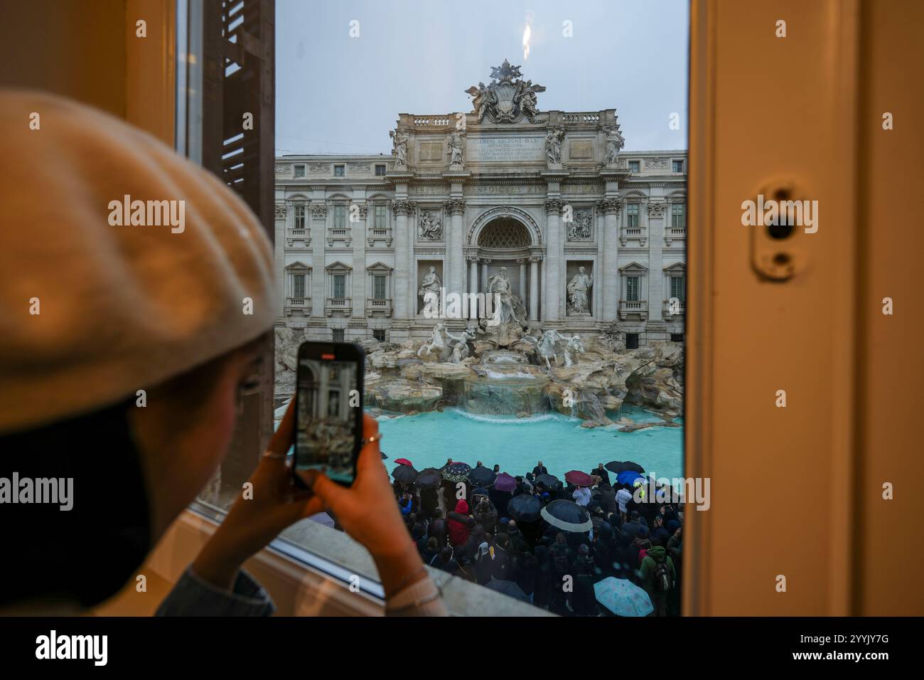 A woman takes a picture of the 18th century Trevi Fountain, one of Rome's most iconic landmarks ...