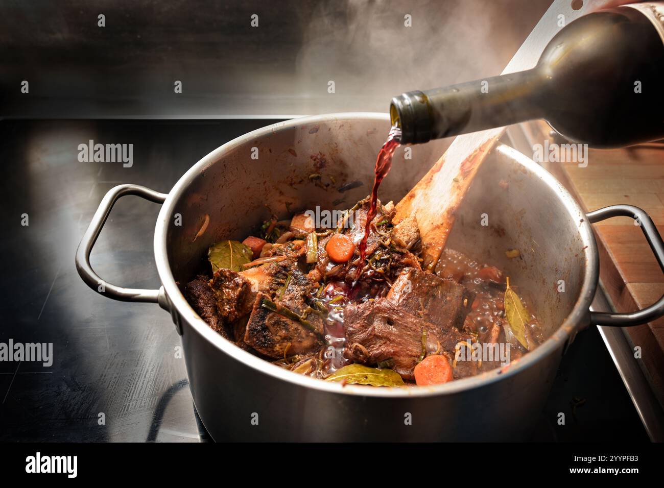 Le vin rouge est versé dans une casserole en acier inoxydable pour ...