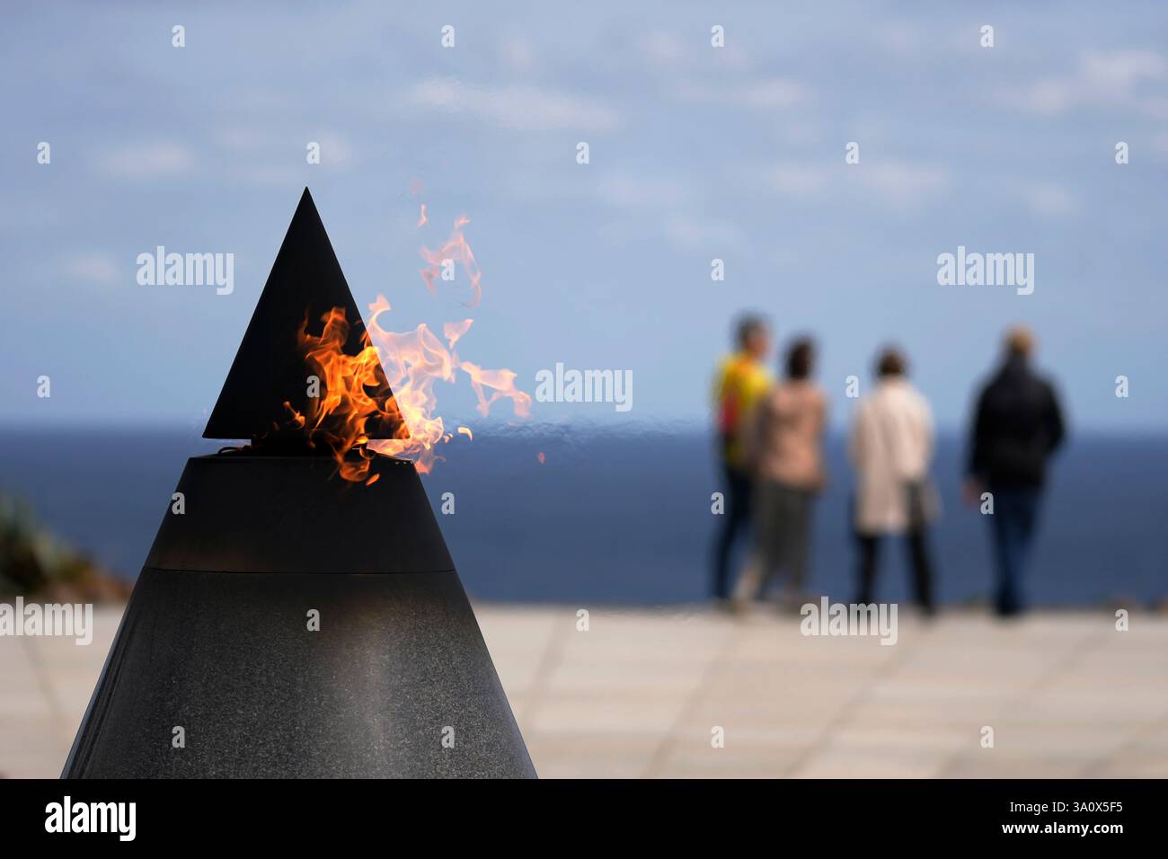 Visitors look at the Philippine Sea, standing near the Flame of Peace ...