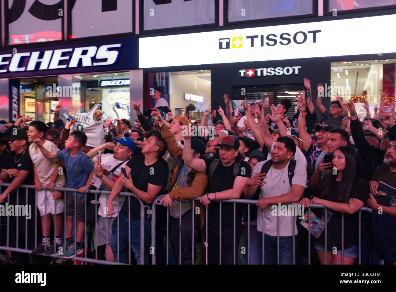 Une foule nombreuse de gens, dont beaucoup les mains levées, se tient ...