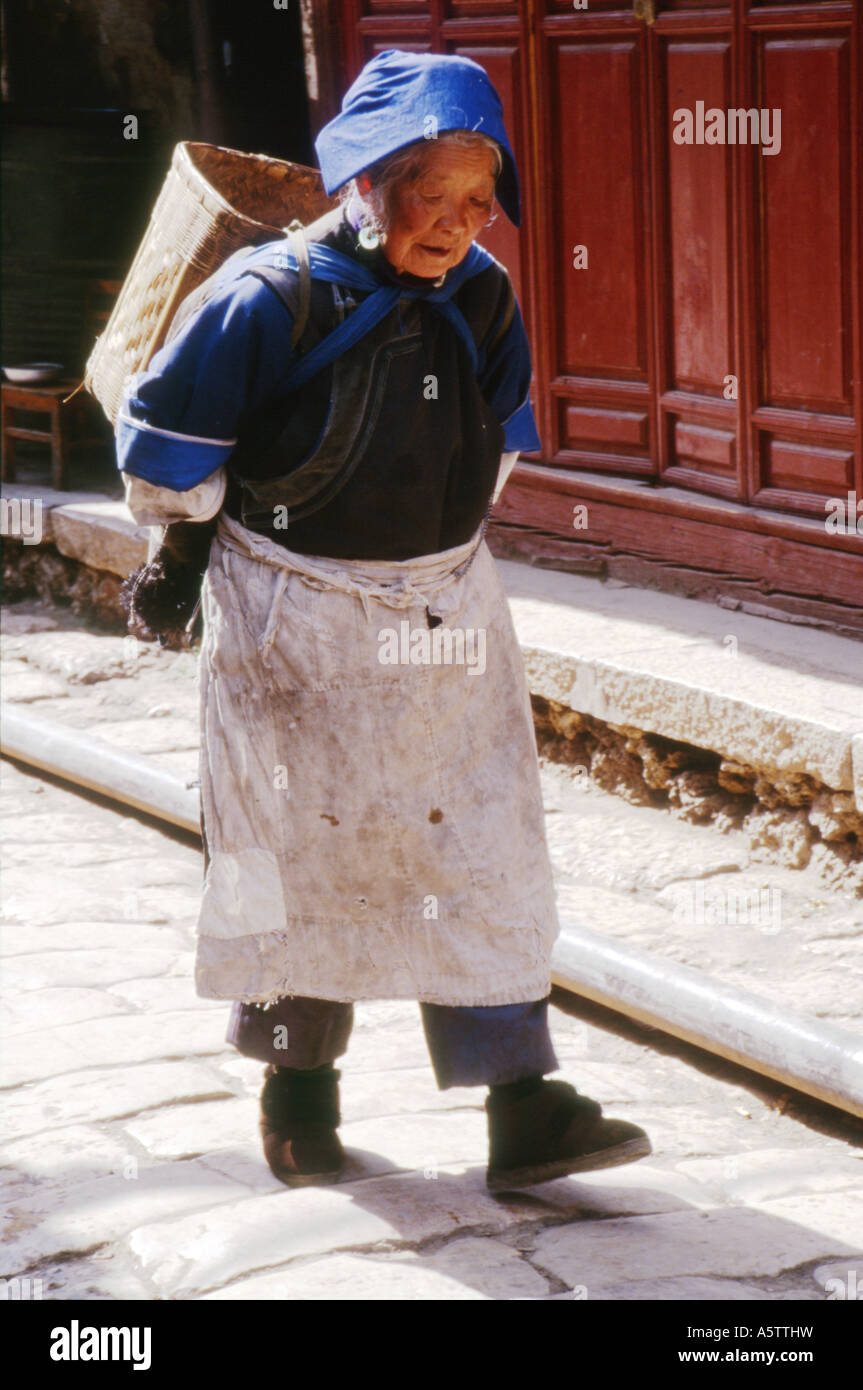 Personnes âgées femme naxi avec panier en osier sur le dos et vêtus de ...
