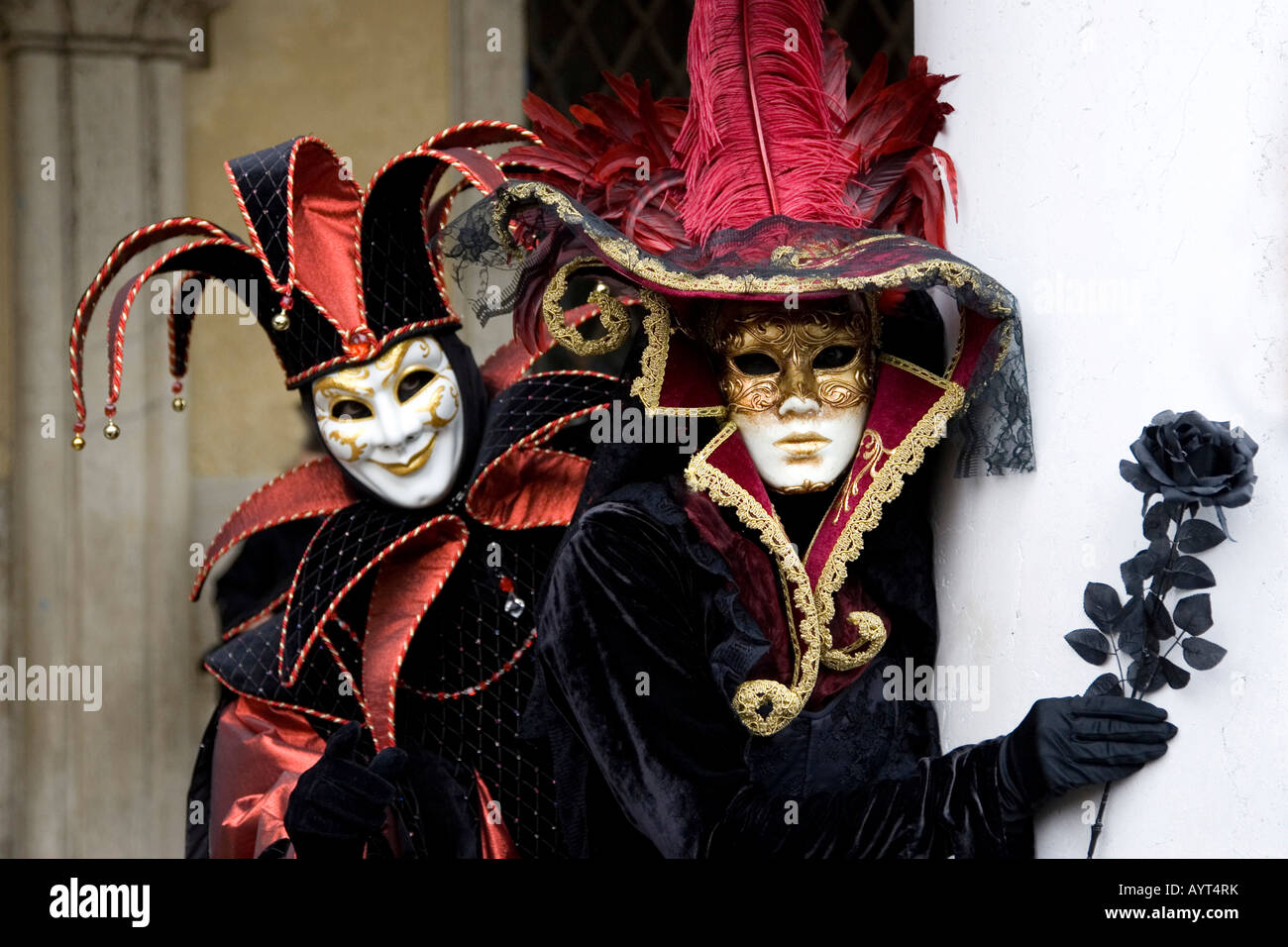 Arlequin (fou) costume et dame élégante avec une rose noire à la main ...