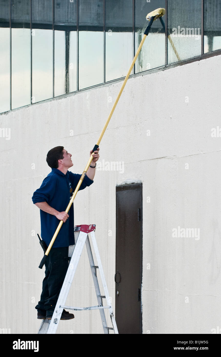 Un jeune enfant raclette lave ontop windows d'une grande échelle Photo ...