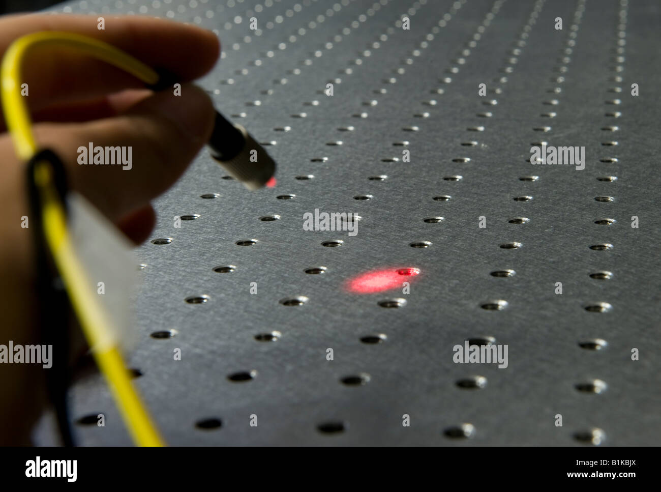 Laser rouge de la lumière émise par une fibre optique sur un banc d ...