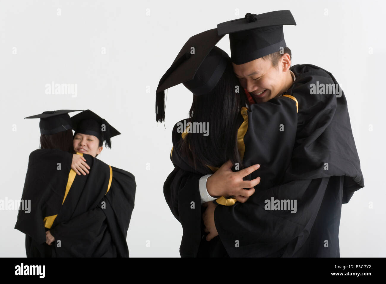 Les jeunes diplômés masculins hugging une femelle et deux femmes ...