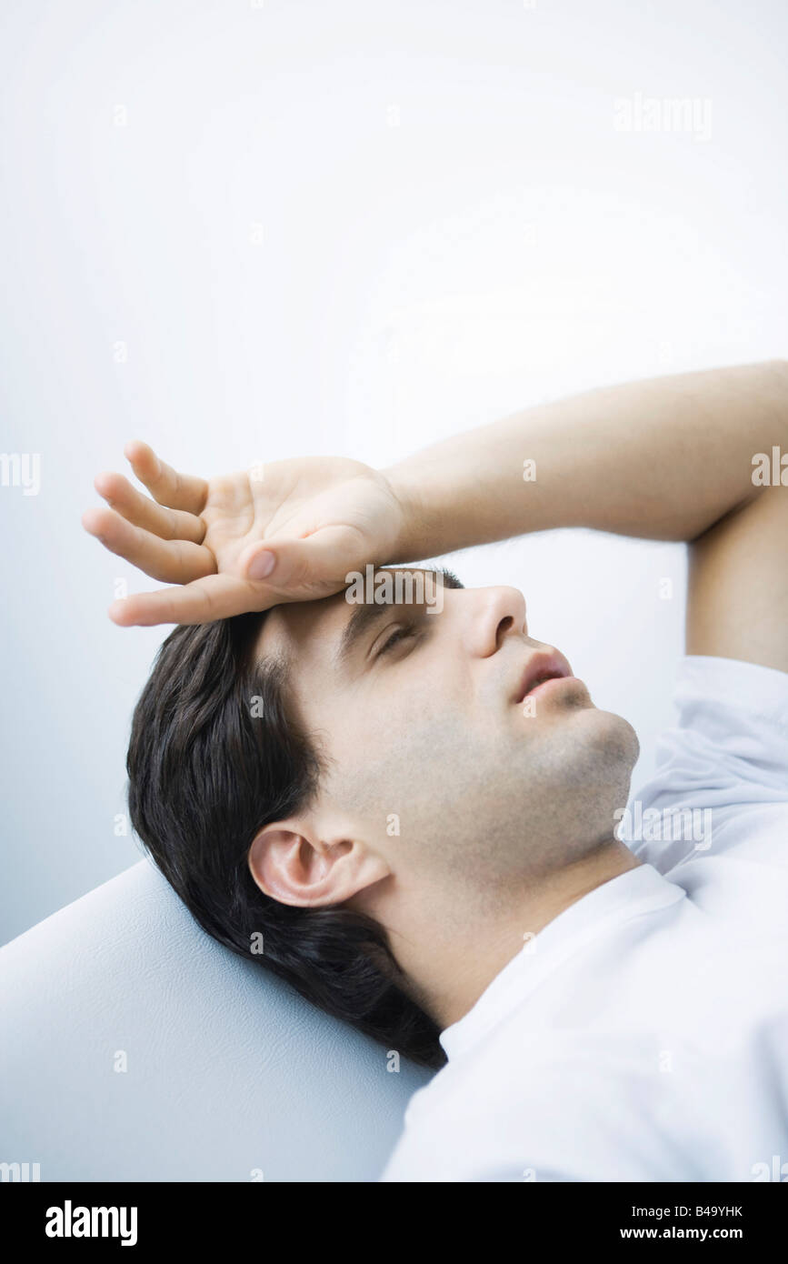 Man reclining avec les yeux fermés, la main sur le front Photo Stock ...