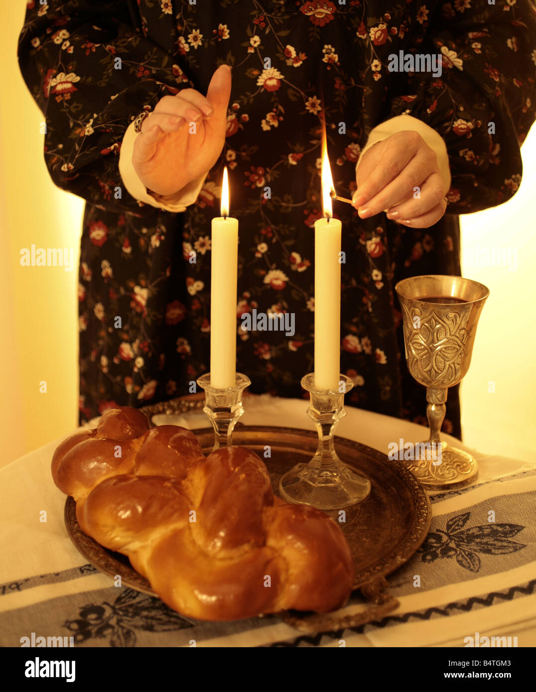 Femme avec un match des bougies d'éclairage, et des symboles du Shabbat ...