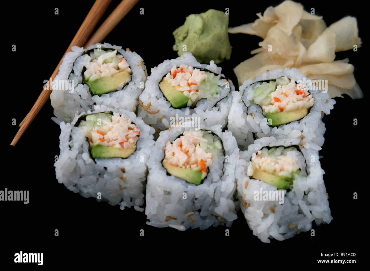 A California roll chouchi isolé sur fond noir avec des baguettes et ...