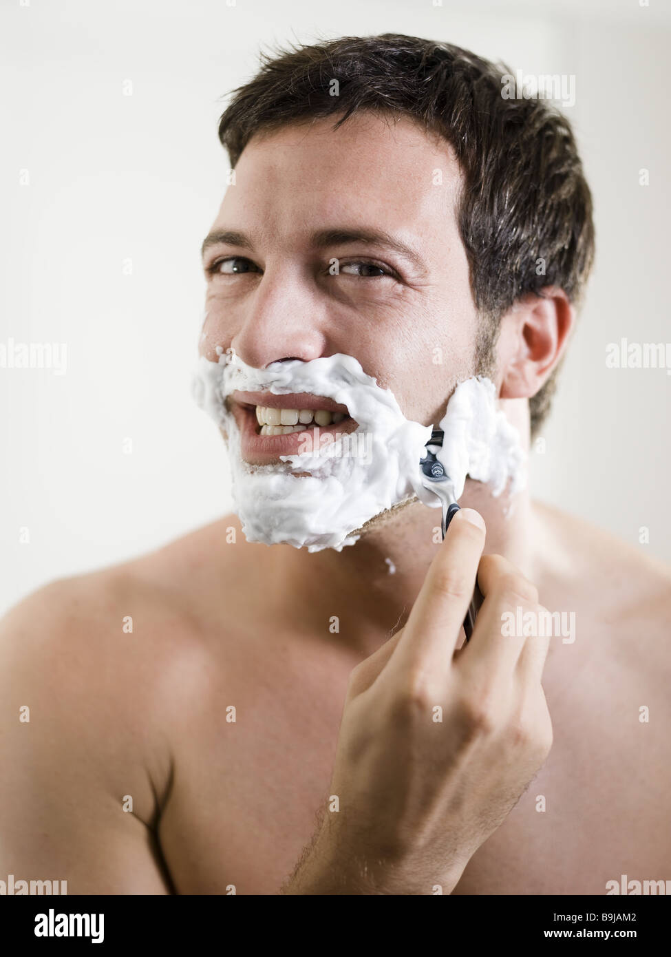L'homme au visage souriant agréablement la crème à raser rasage ...