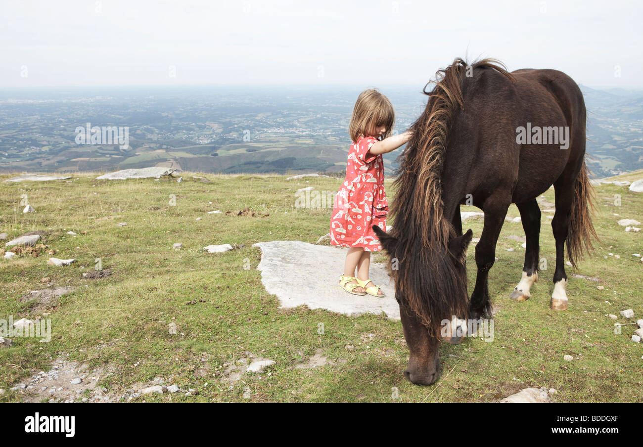 Petite fille de flatter un poney Pottok sauvages sur la Rhune et point ...