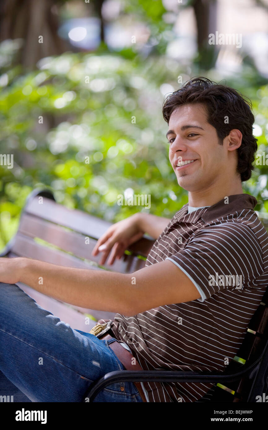 Portrait d'un jeune homme assis sur un banc avec sa main sur son genou ...