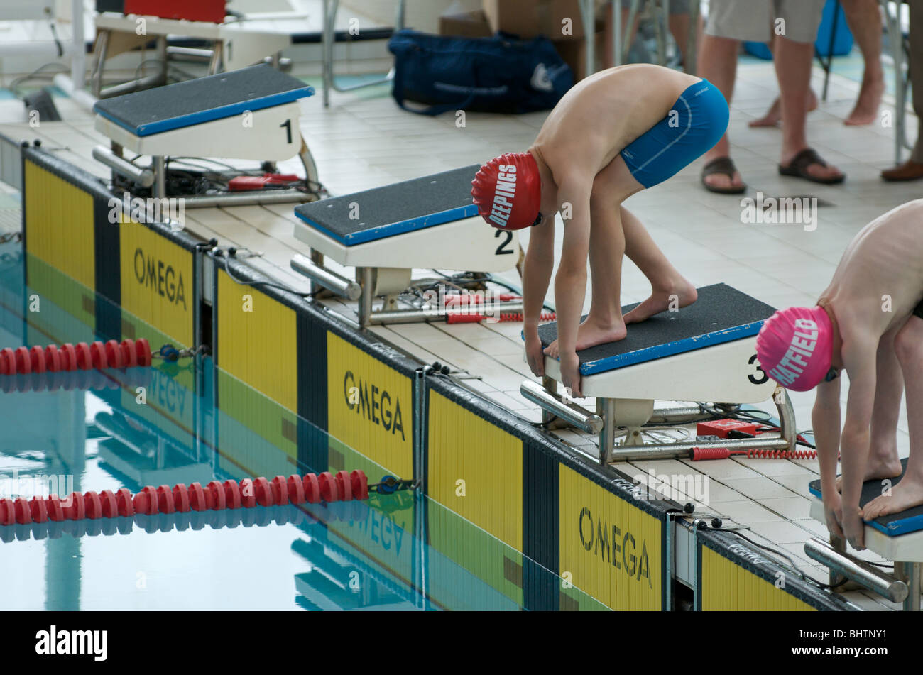 Garçon sur le bloc de départ au début d'une course de natation Photo ...