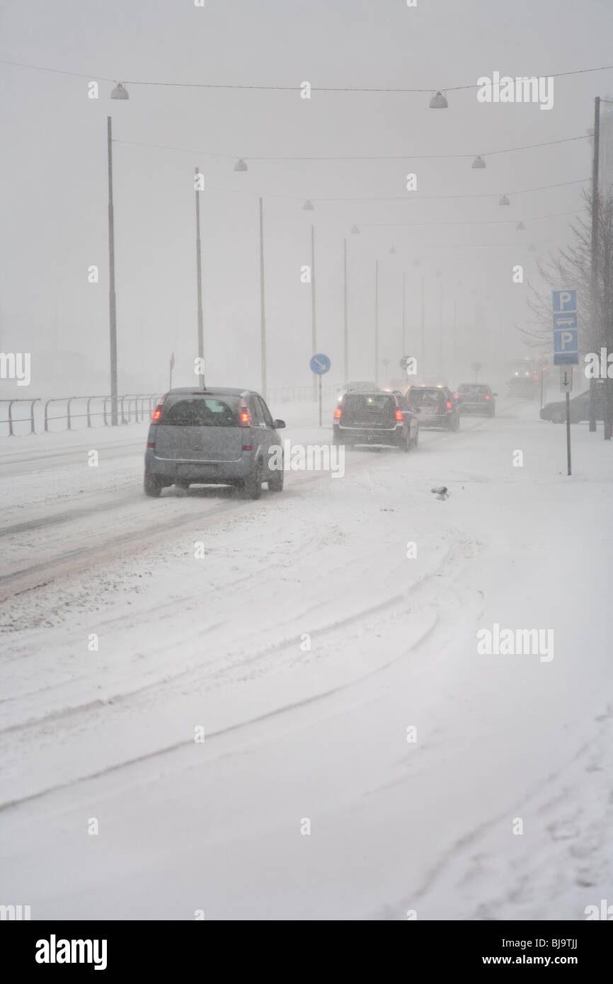La circulation dans une rue couverte de neige dans une tempête de neige ...