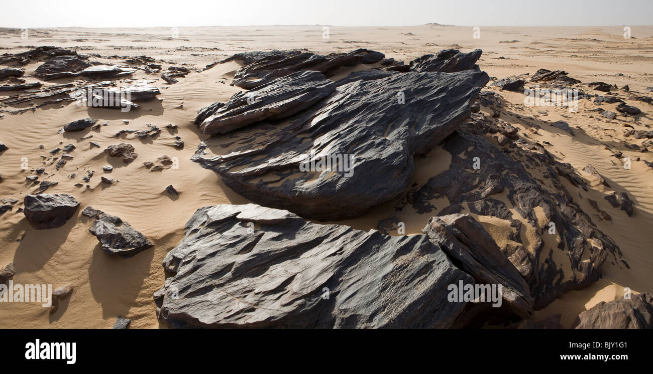 Rochers noirs en sol du désert dans le Gilf Kebir National Park ...